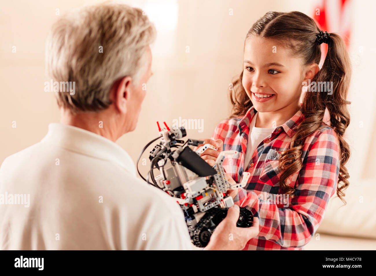Smiling girl looking at grandfather holding robot toy Stock Photo - Alamy