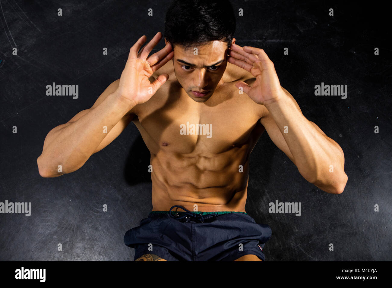 An Asian muscular fitness model performing abdominal crunches. Overhead ...