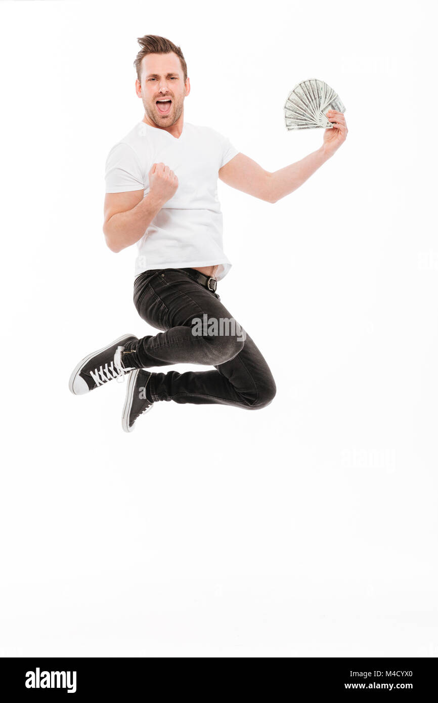 Photo of excited young man jumping isolated over white background ...