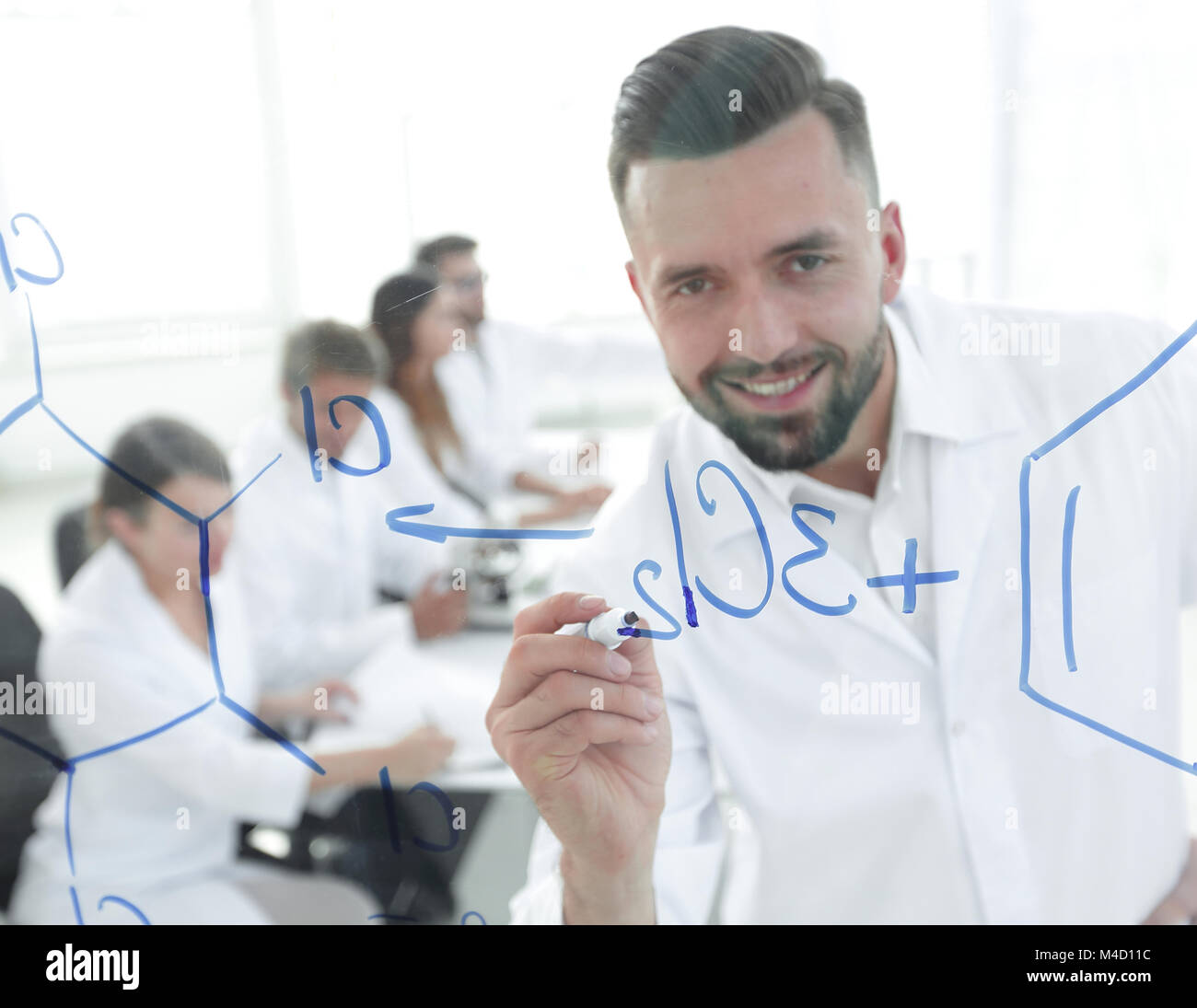 close up of a smiling scientist writes a formula on the blackboard ...