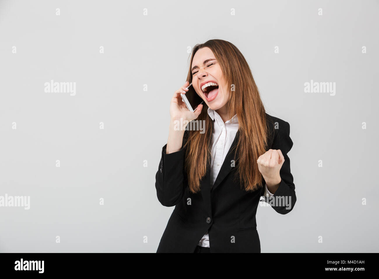 Happy pretty lady screaming and showing winner gesture while talking on ...