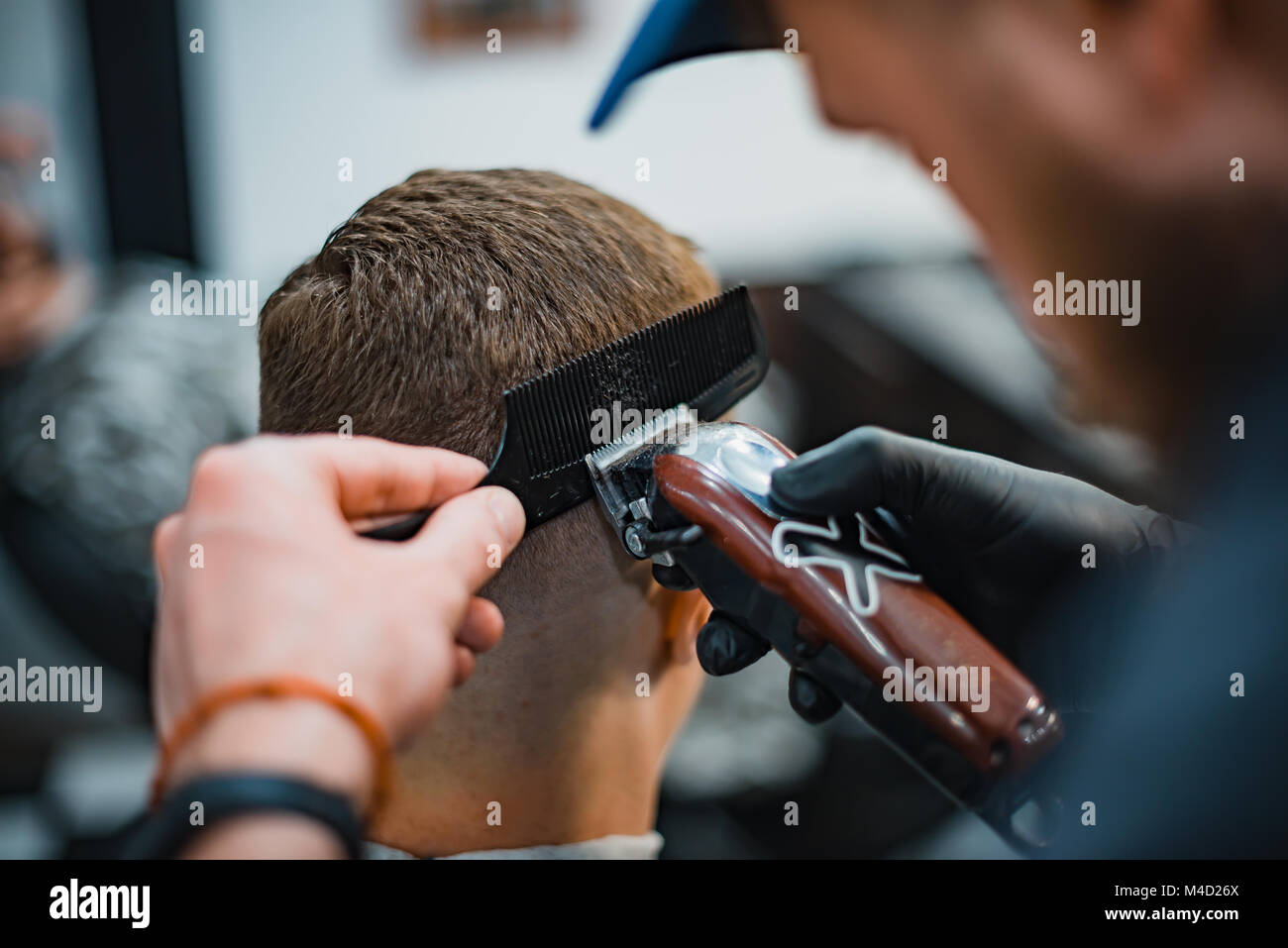 Man gets a cool haircut in barbershop. Barber makes the cut man ...
