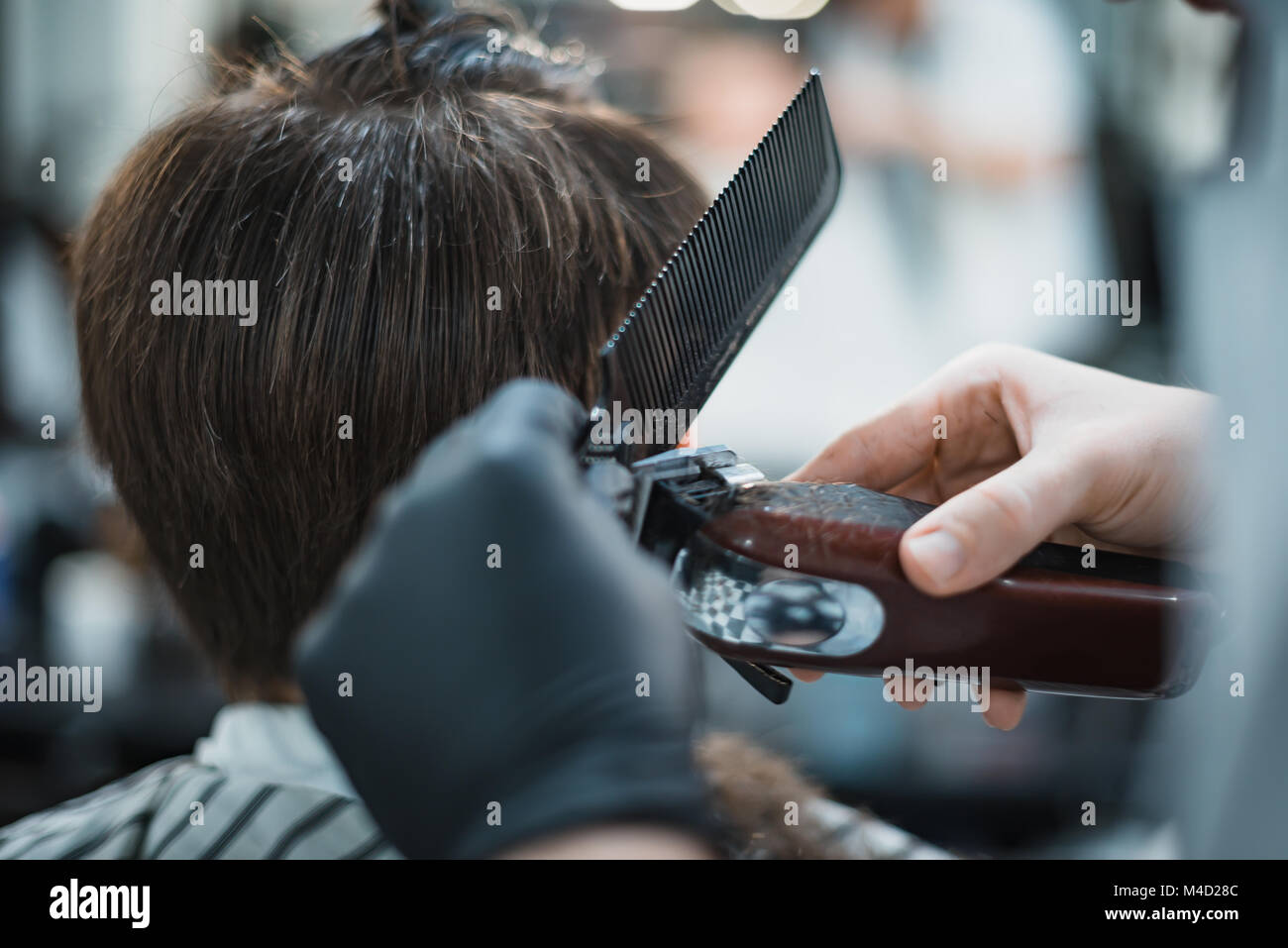 Man gets a cool haircut in barbershop. Barber makes the cut man ...