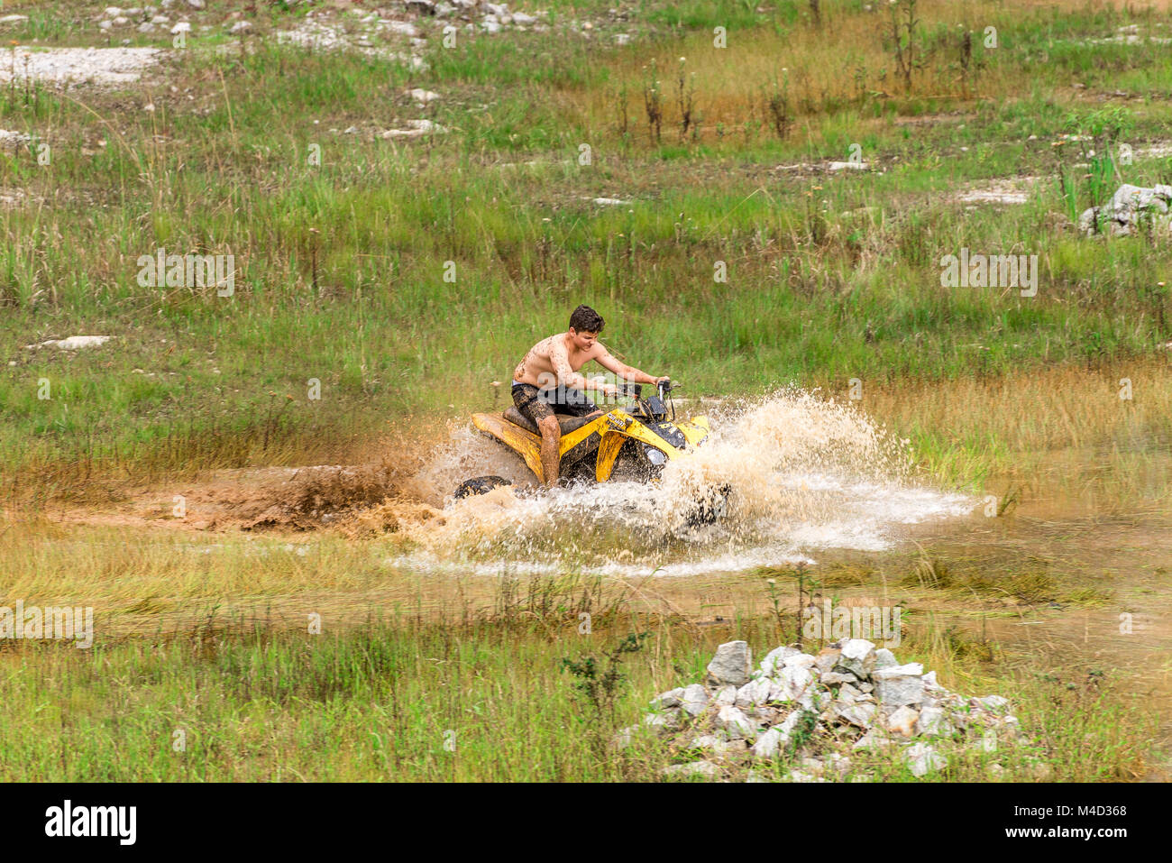 Off road on quad bike rally over mud puddle Stock Photo - Alamy