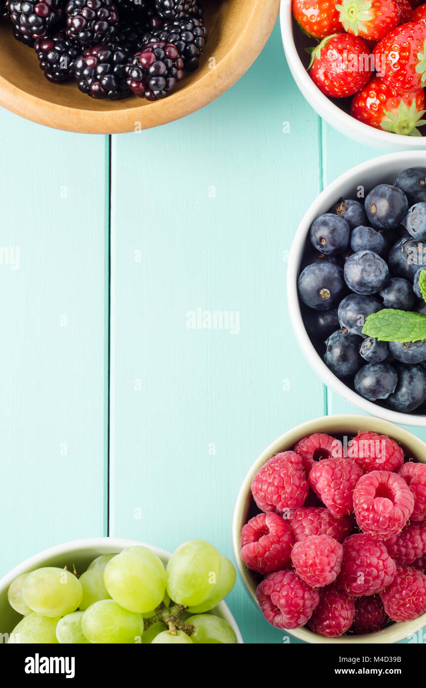 Overhead shot of five fruit varieties in separate bowls bordering frame ...
