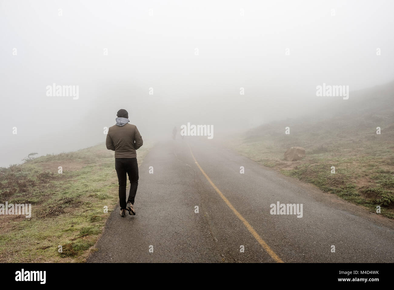 Lone man walking through the white fog Stock Photo - Alamy