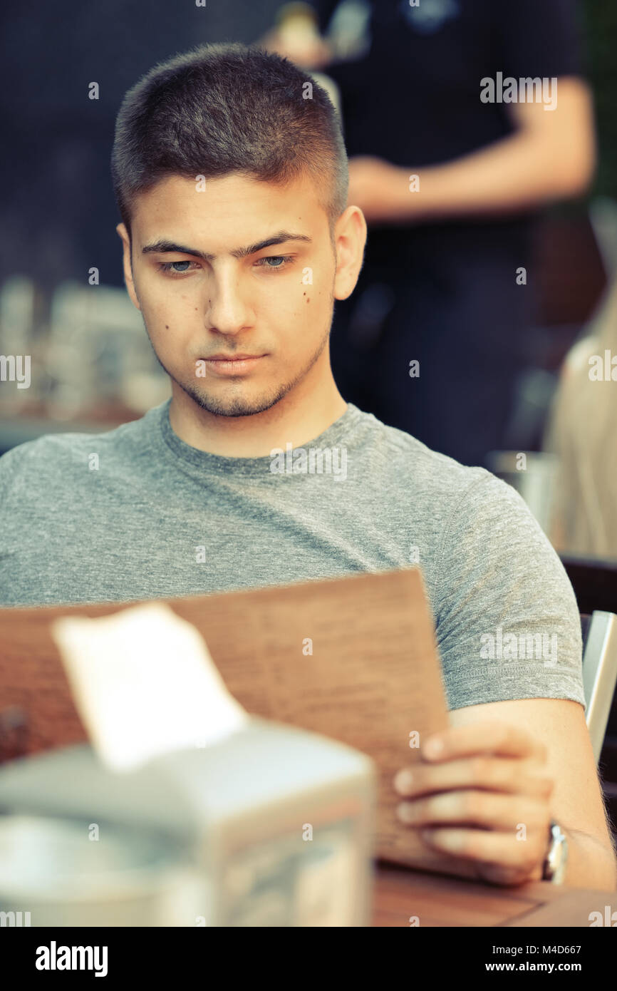 Man in outdoor restaurant looking at the menu Stock Photo - Alamy