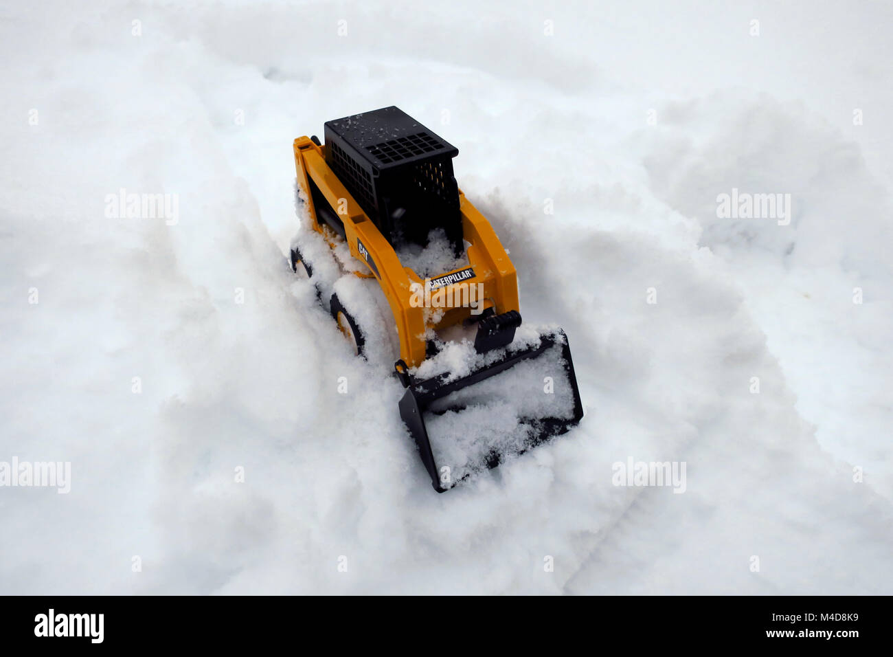 A small yellow toy loader moving snow. Concept Stock Photo - Alamy