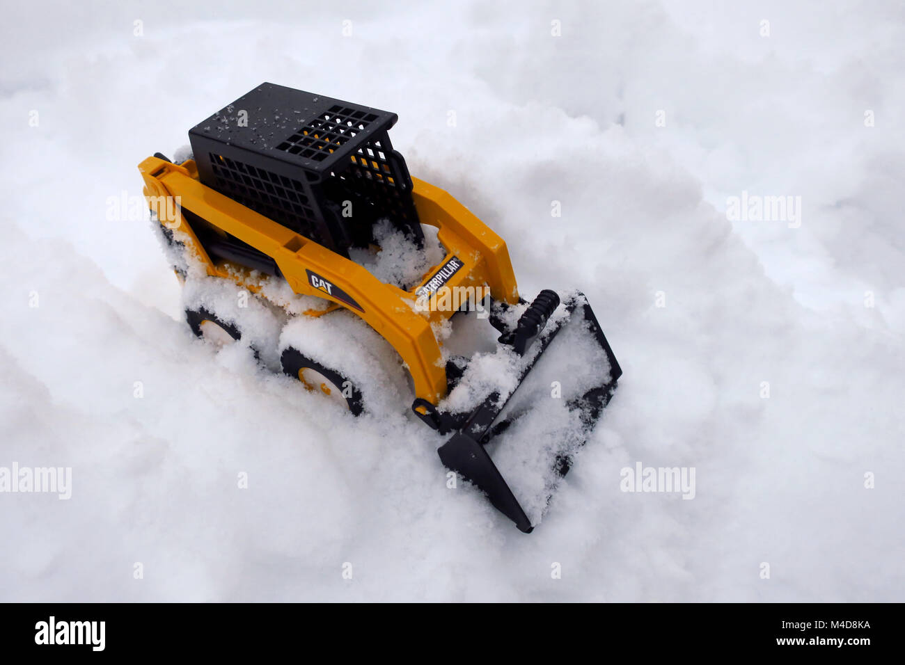 A small yellow toy loader moving snow. Concept Stock Photo - Alamy