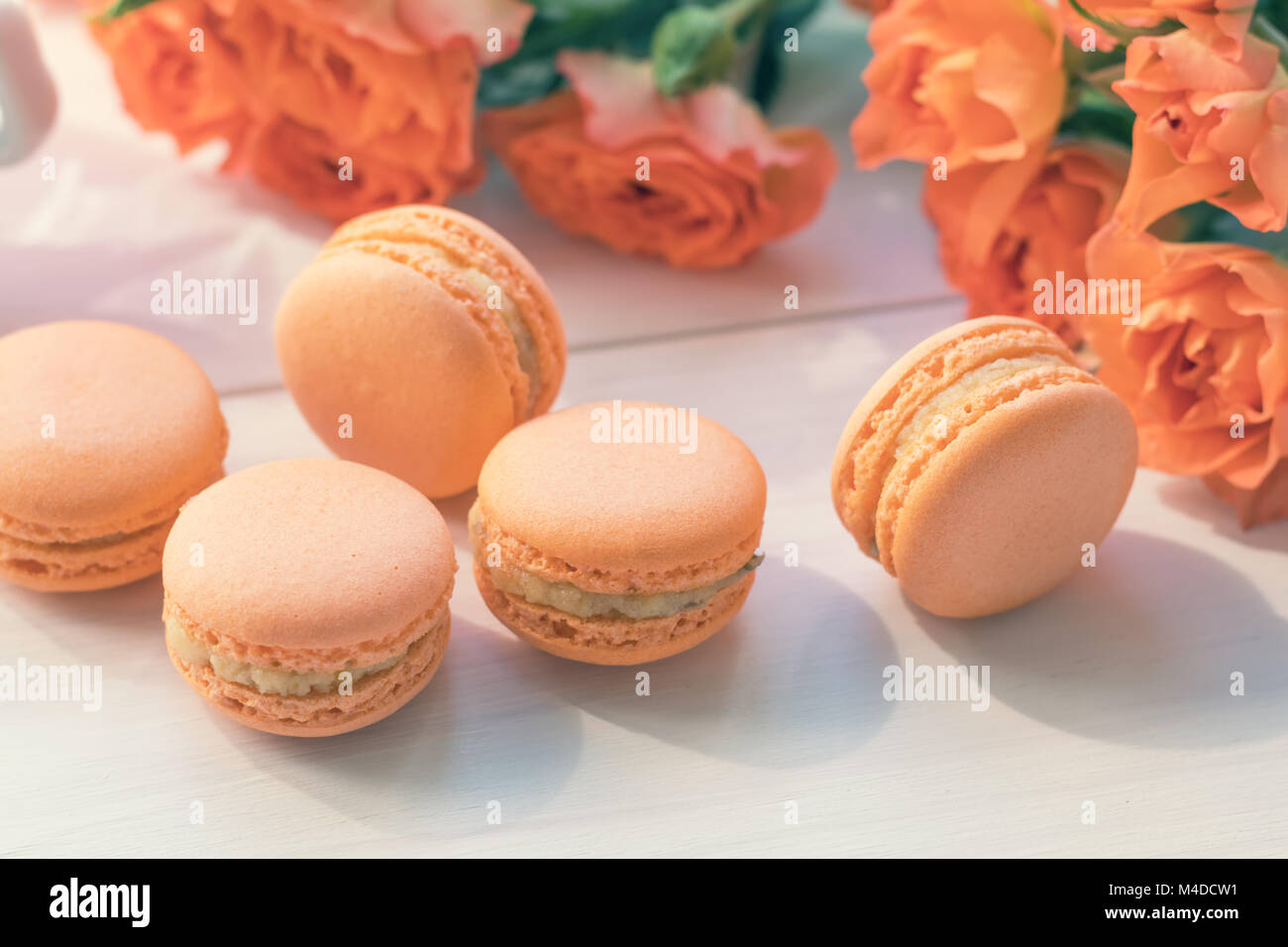 Orange macaroons and fresh little roses Stock Photo - Alamy