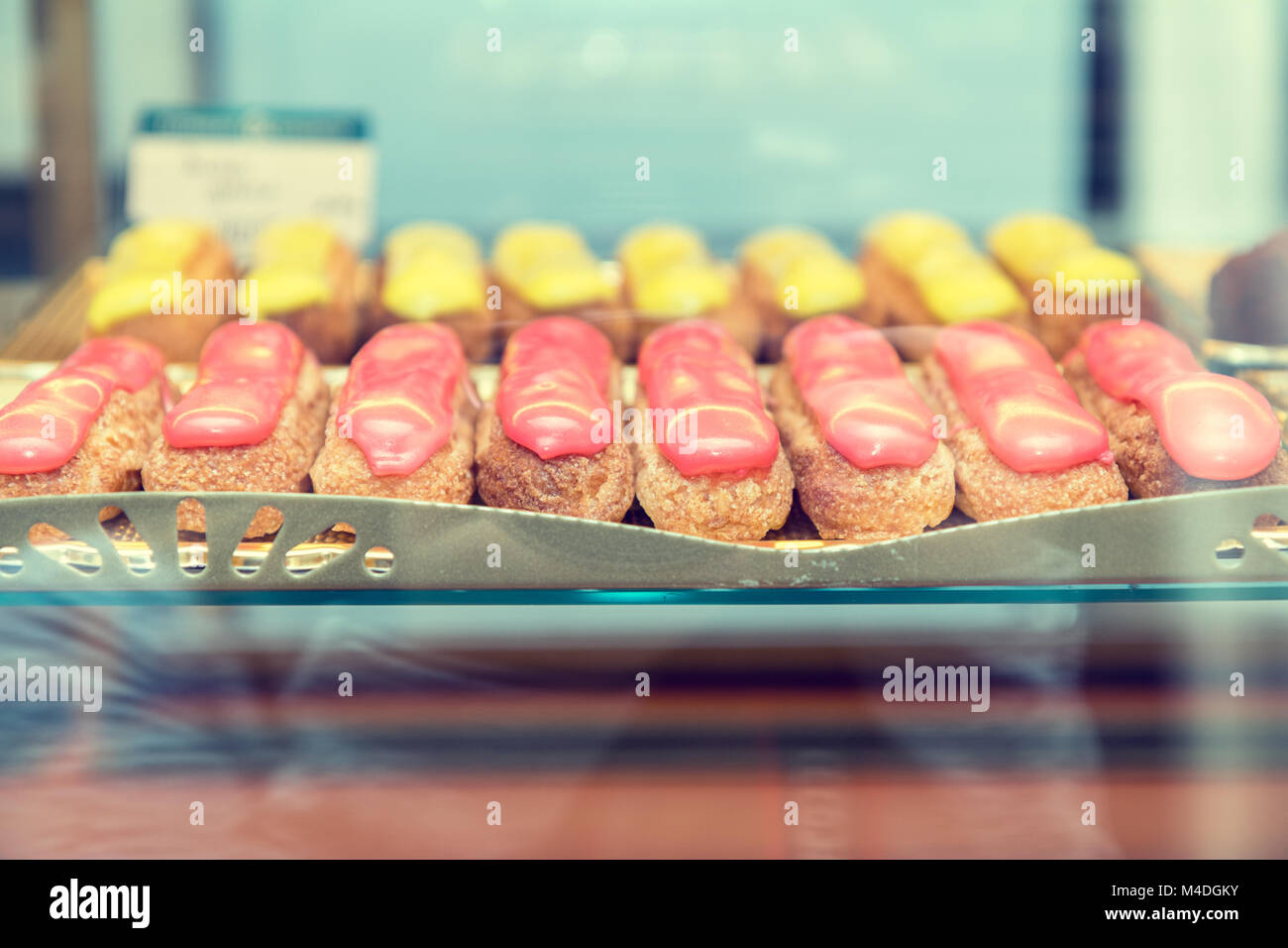 Eclairs with red and yellow glaze Stock Photo - Alamy