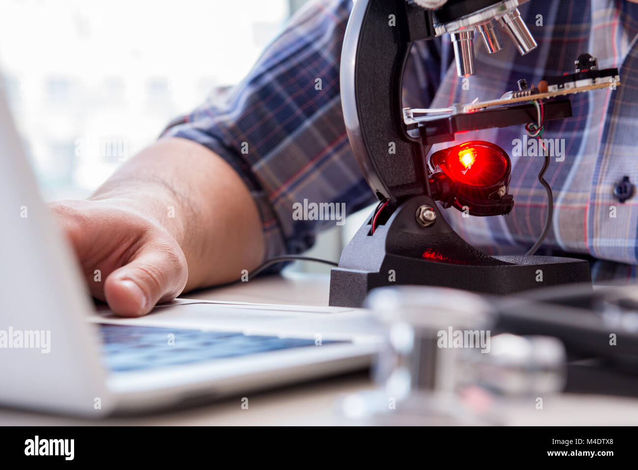 High precision engineering with man working with microscope Stock Photo ...