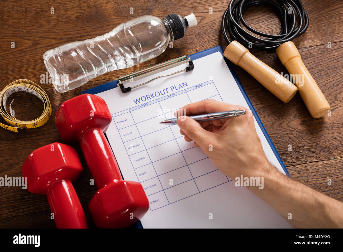 Close-up Of Person Hand Filling Workout Plan Form With Workout ...