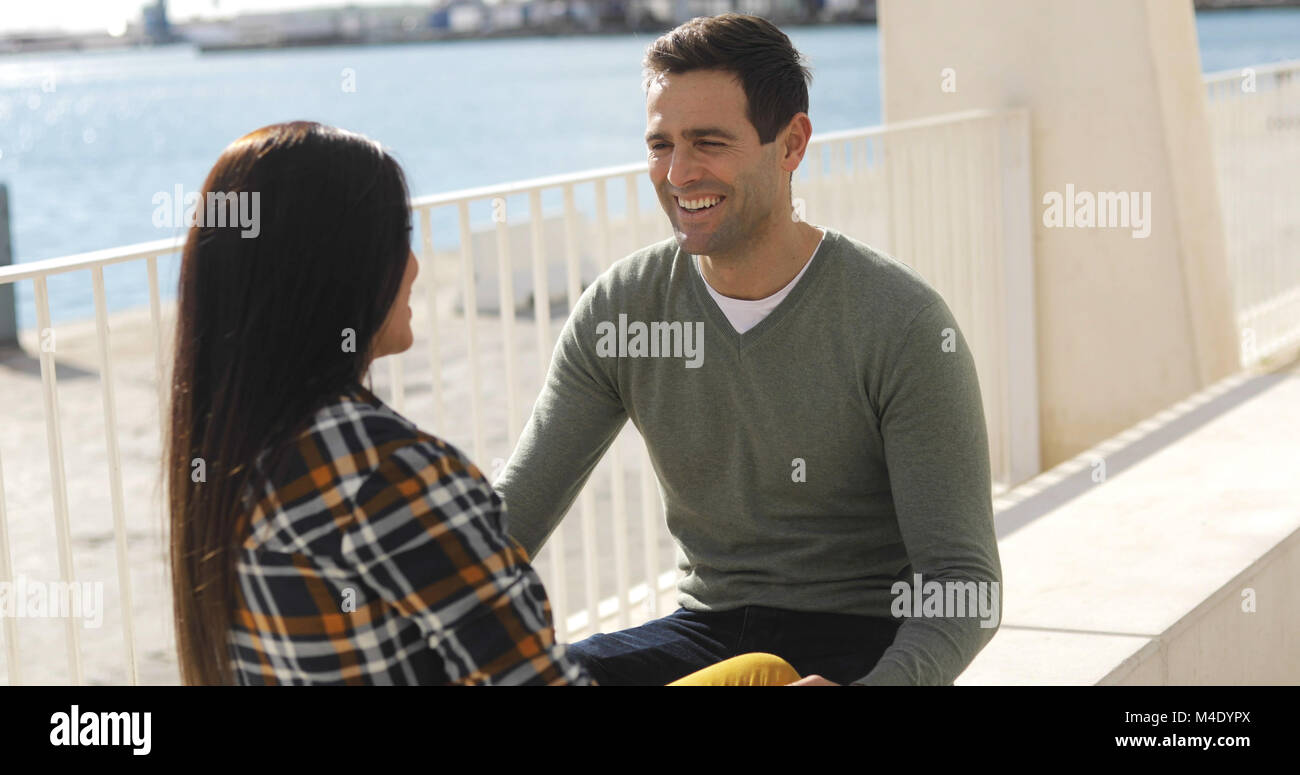 Young man and woman sitting chatting at a quay Stock Photo - Alamy
