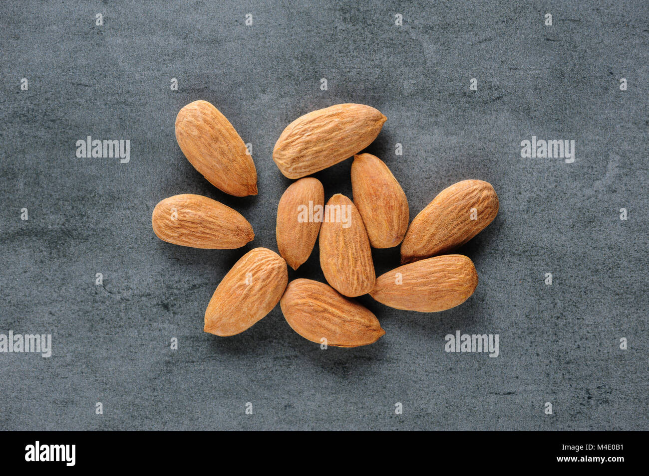 Almonds scattered over dark stone board Stock Photo - Alamy