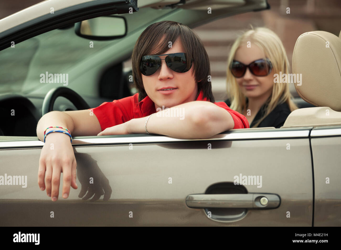 Happy young couple driving convertible car Stock Photo - Alamy