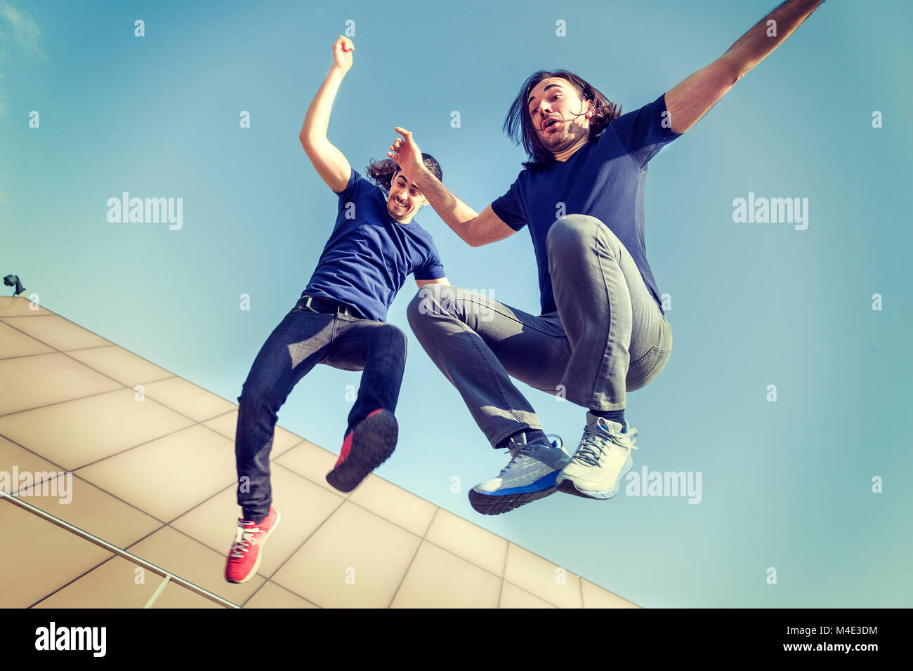 happy young adults jumping on a terrace Stock Photo - Alamy