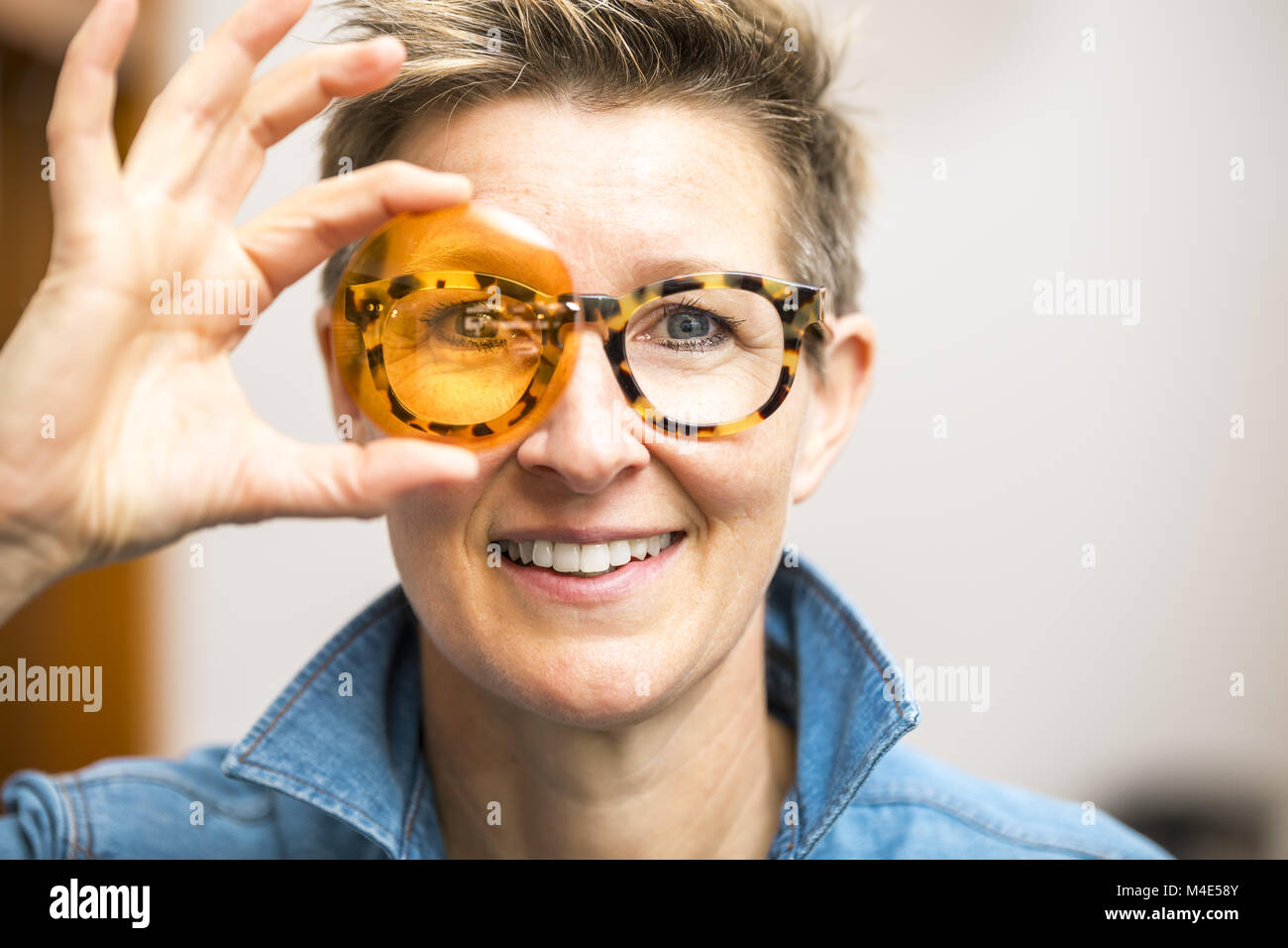 woman with glasses looking through orange glass Stock Photo - Alamy