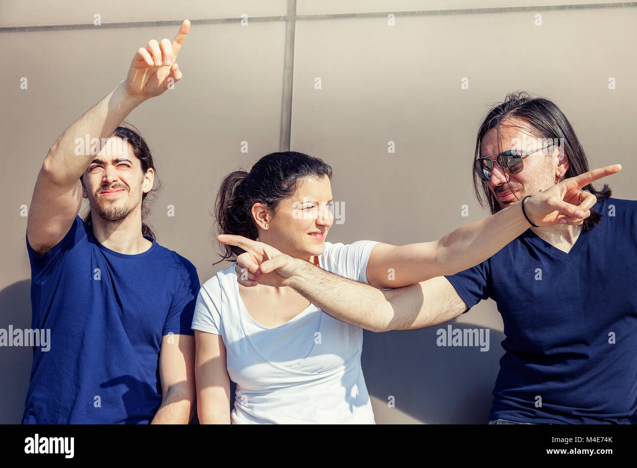 group of three young friends pointing different directions with their ...
