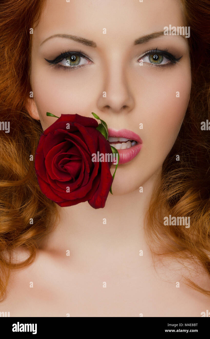 rose in the teeth of woman with red hair Stock Photo - Alamy