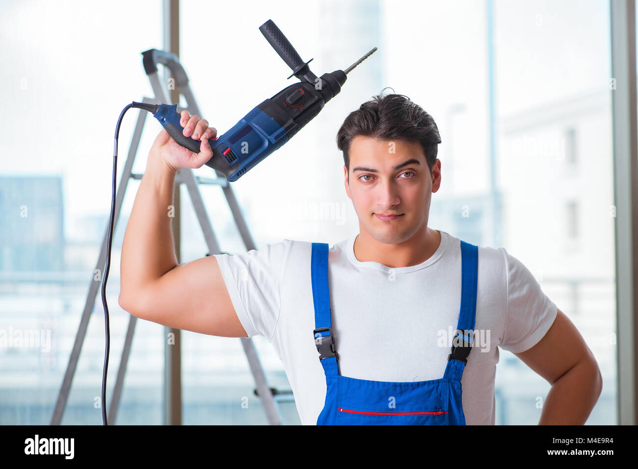 Young worker with hand drill Stock Photo - Alamy