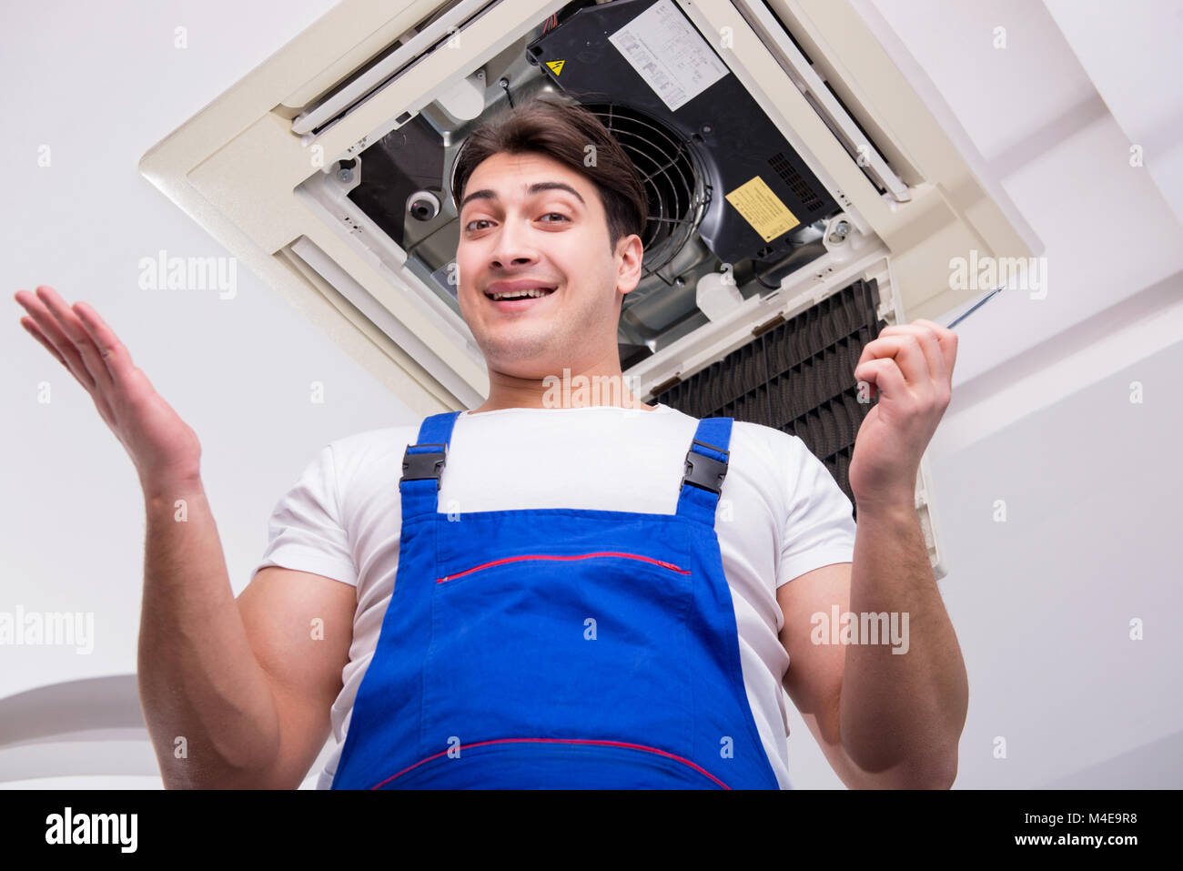 Worker repairing ceiling air conditioning unit Stock Photo - Alamy
