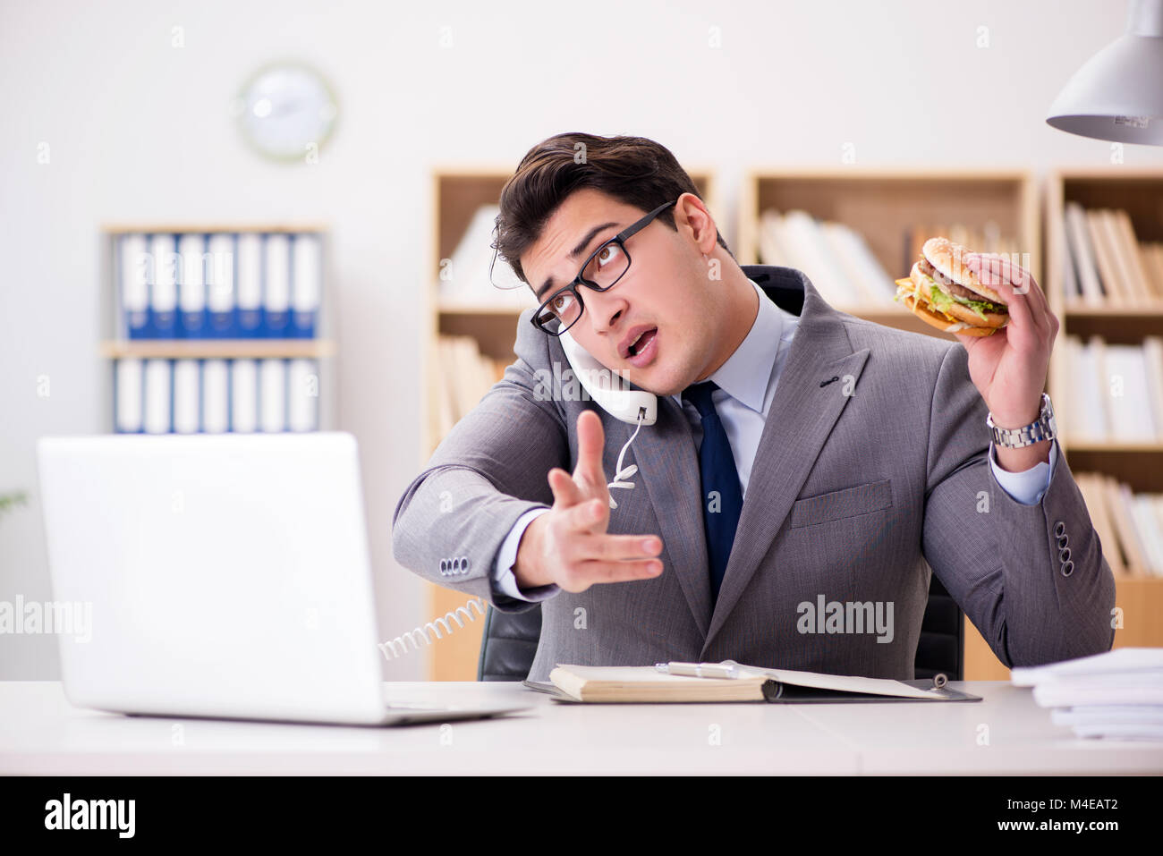 Hungry funny businessman eating junk food sandwich Stock Photo - Alamy