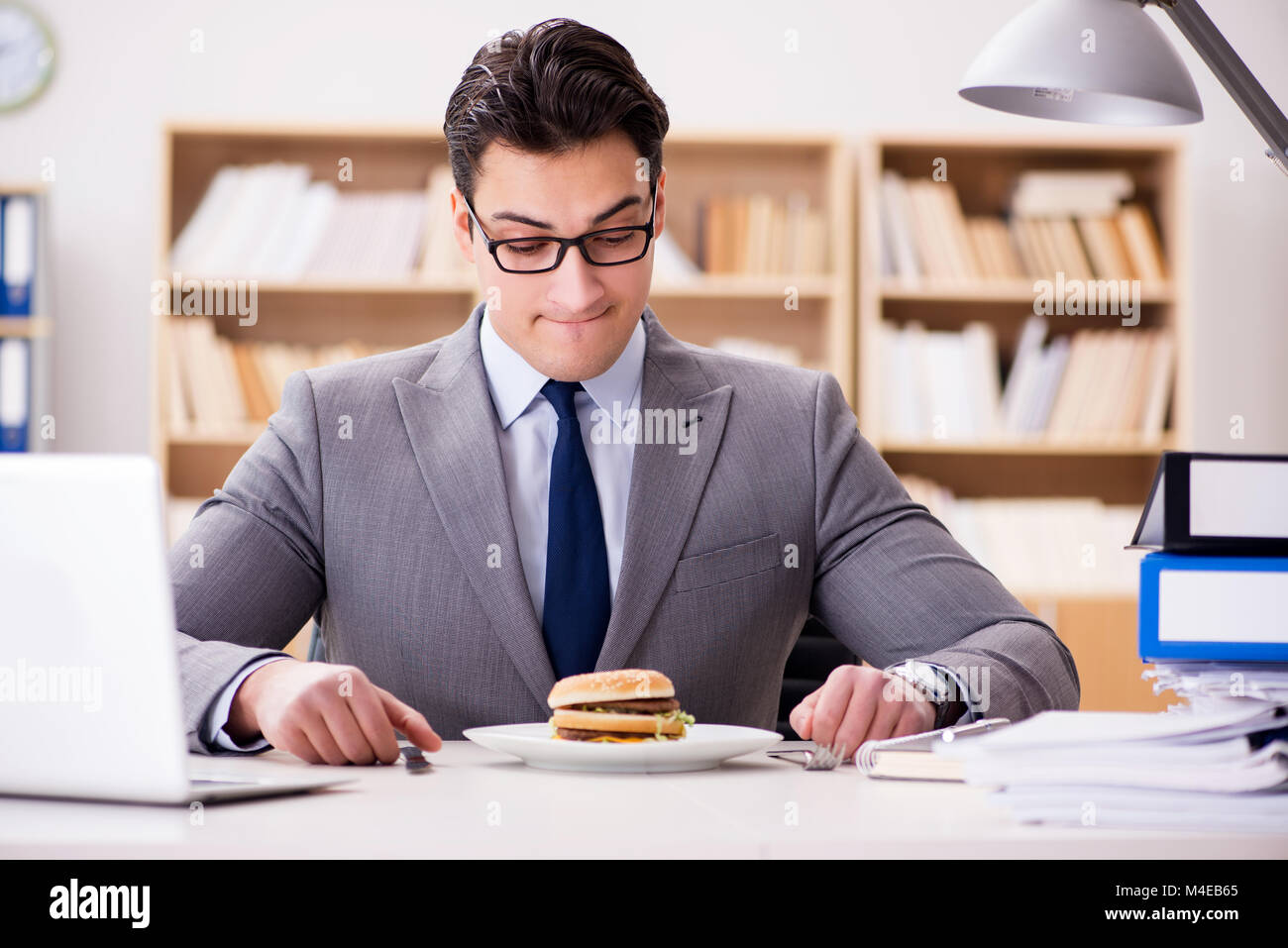 Hungry funny businessman eating junk food sandwich Stock Photo - Alamy