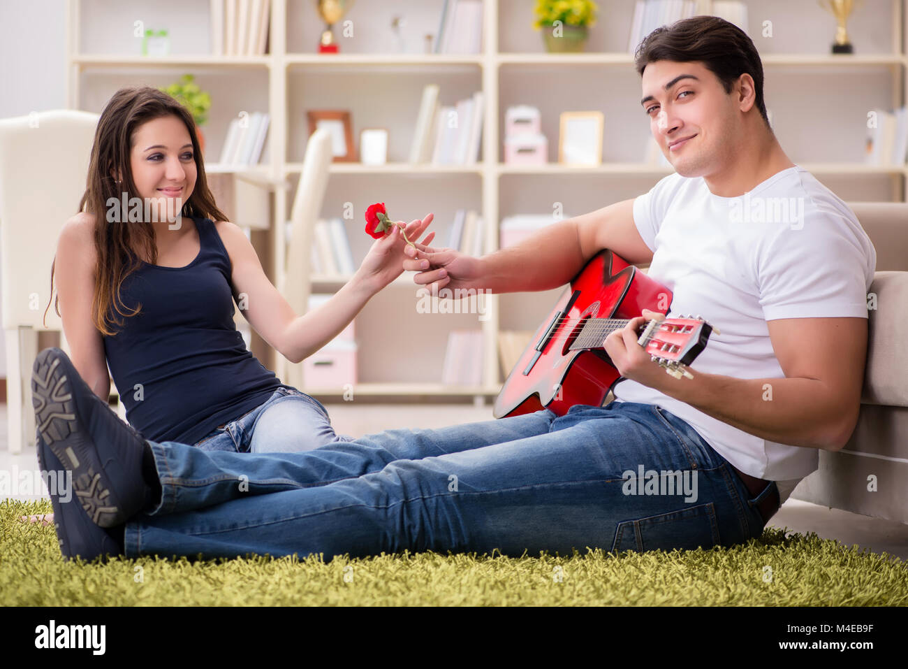 Romantic pair playing guitar on floor Stock Photo - Alamy