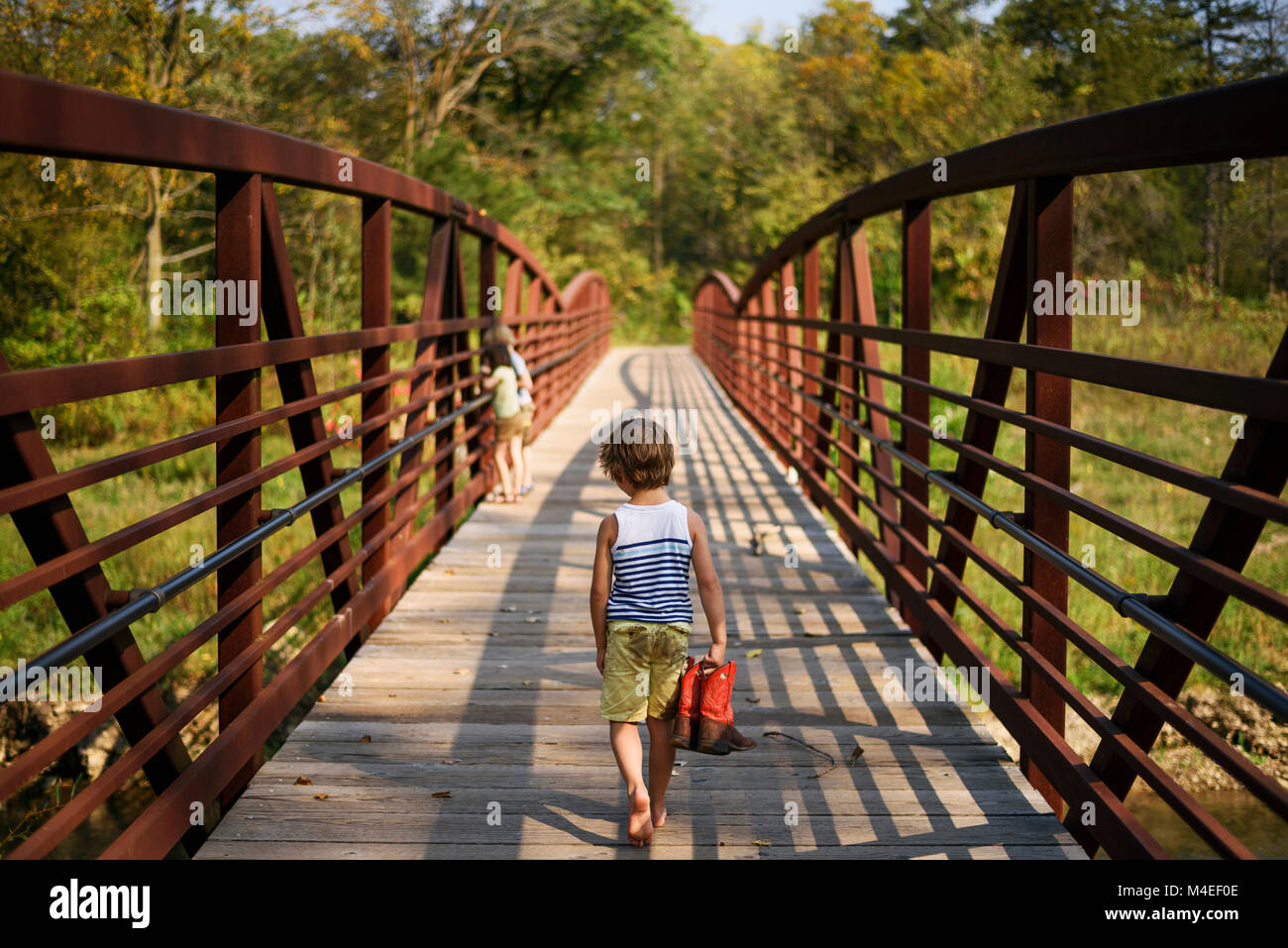 Three children walking across a bridge Stock Photo - Alamy