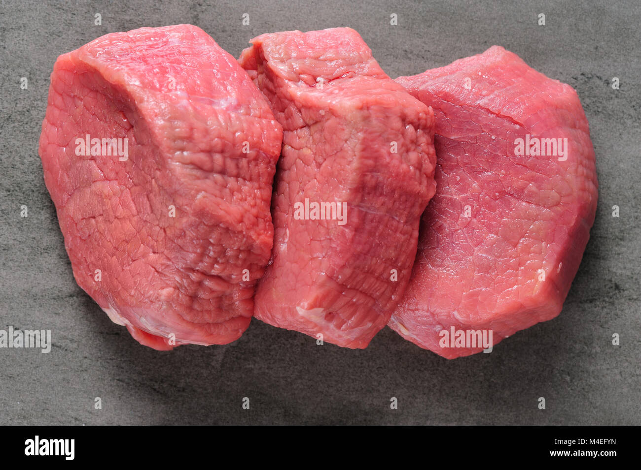 three piecea of raw beef meat on shale board Stock Photo - Alamy