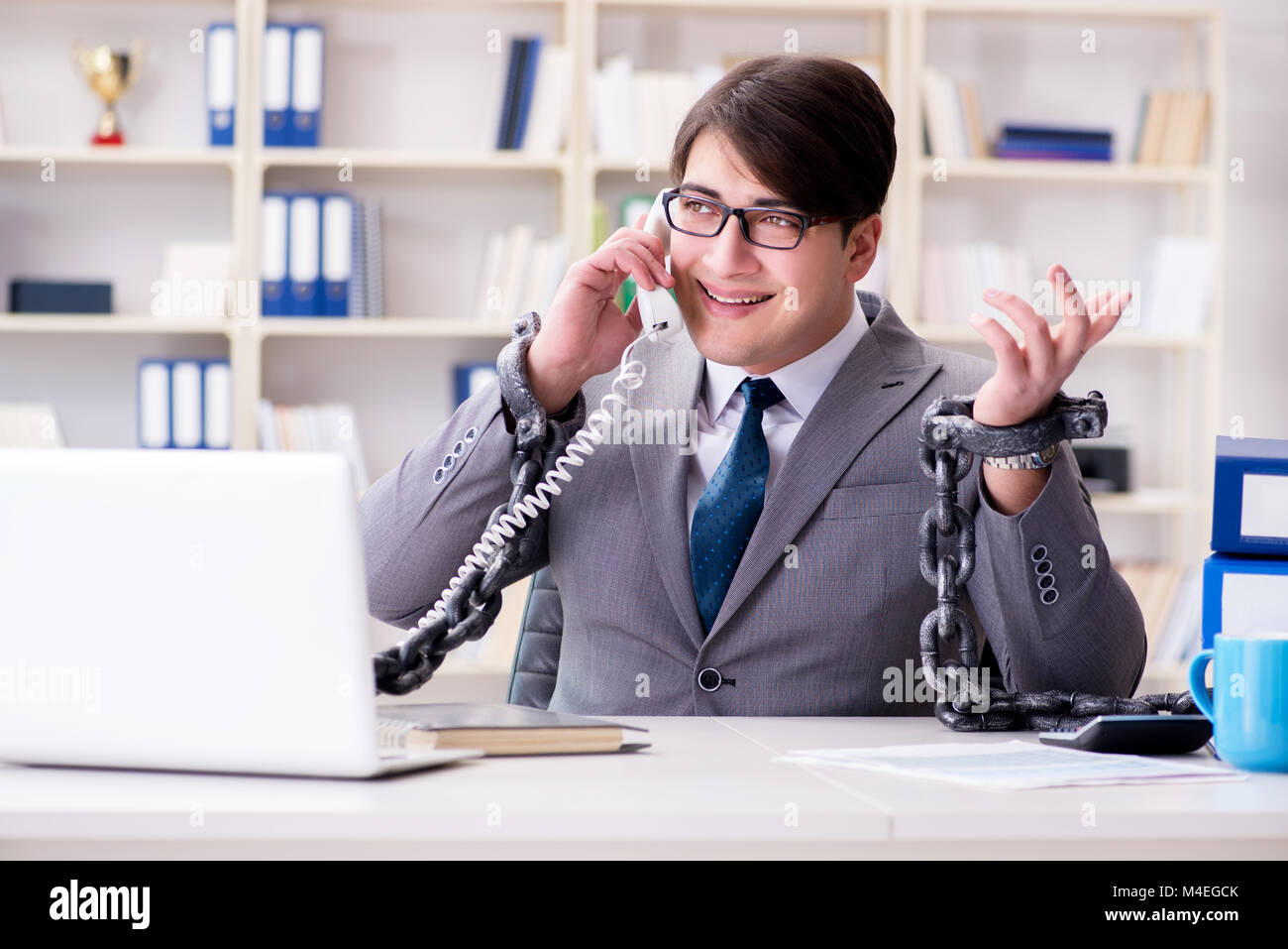 Businessman tied with chains to his work Stock Photo - Alamy