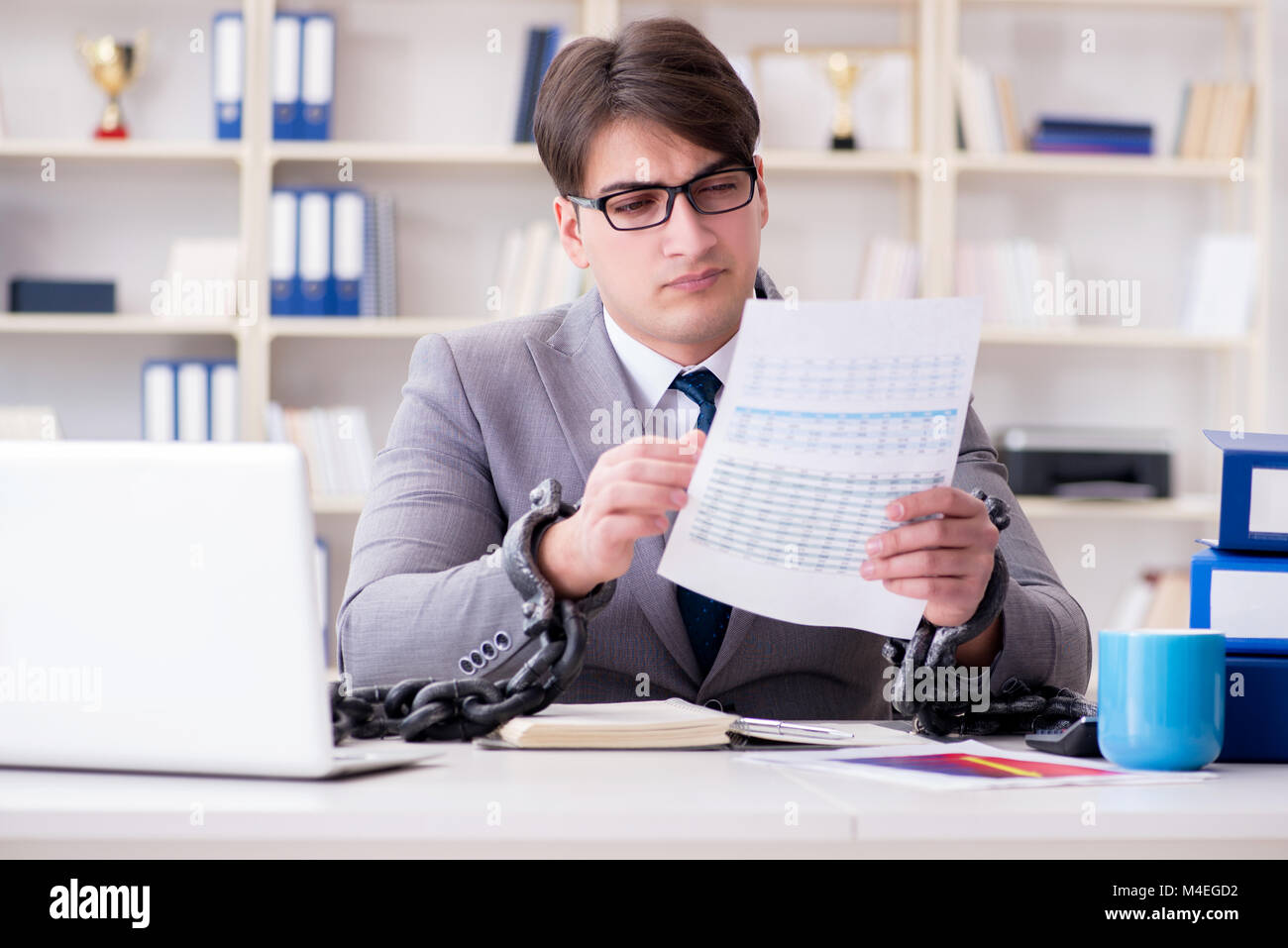 Businessman tied with chains to his work Stock Photo - Alamy