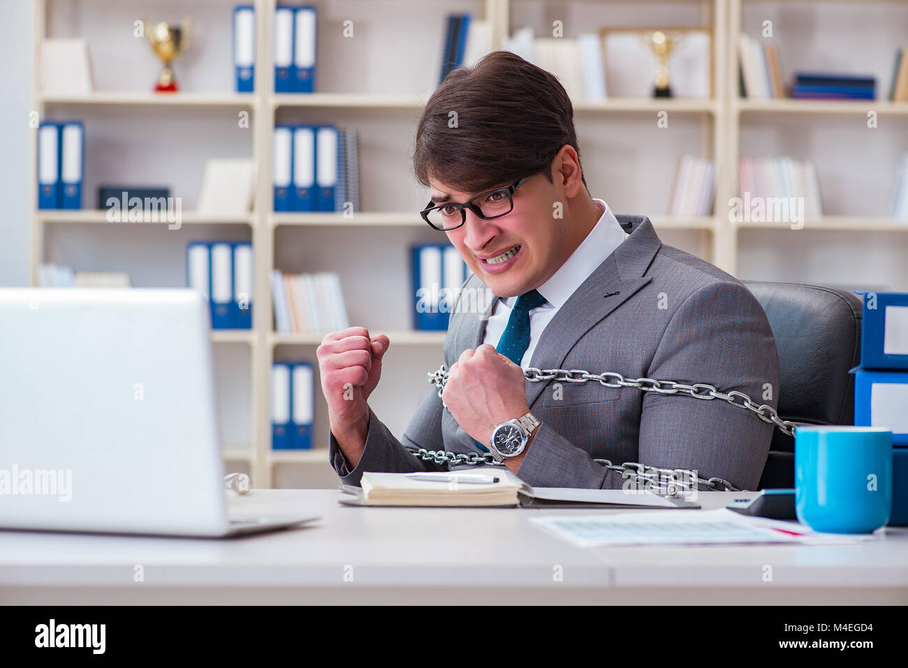 Businessman tied with chains to his work Stock Photo - Alamy