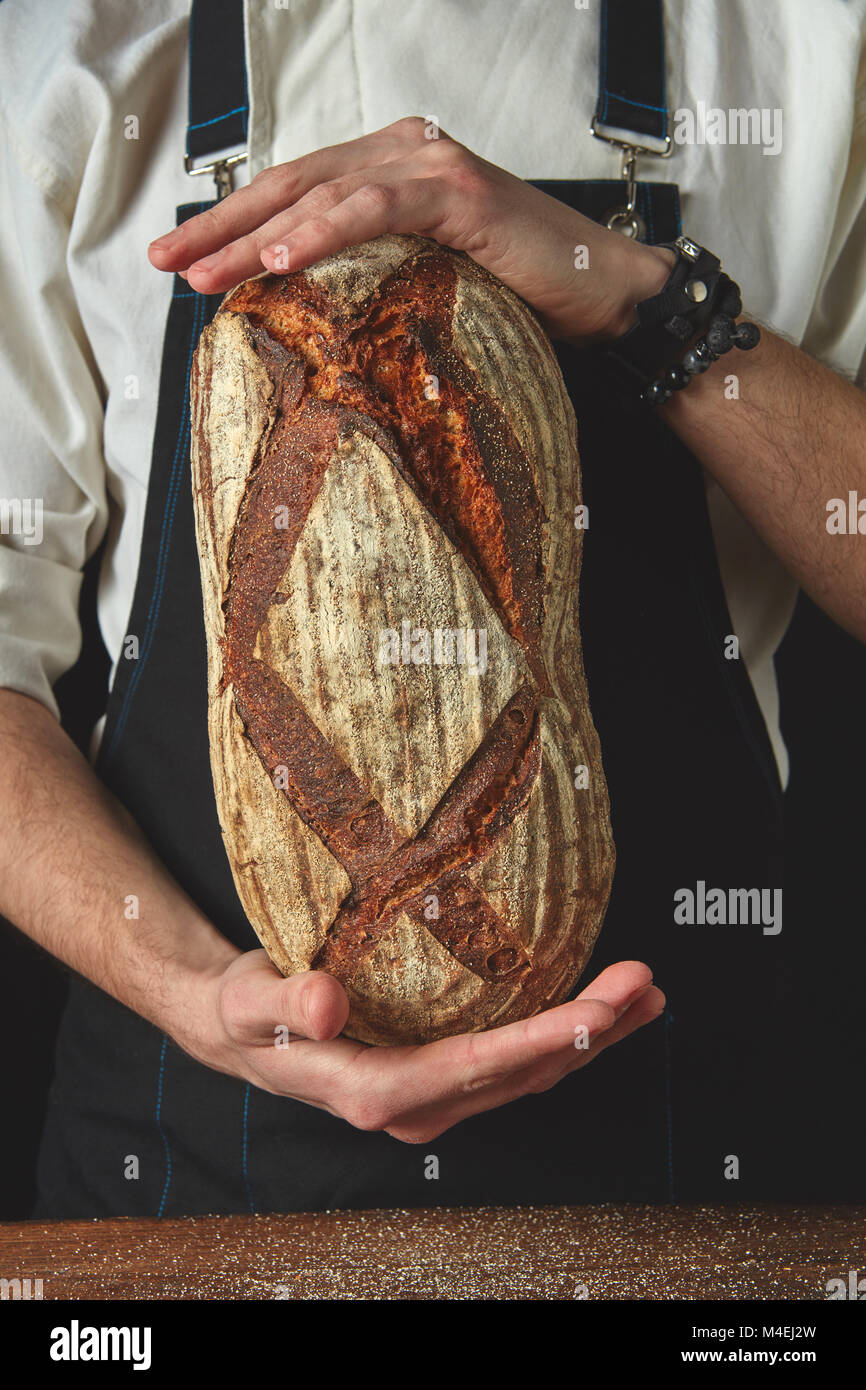 Hands of man holding oval bread Stock Photo - Alamy