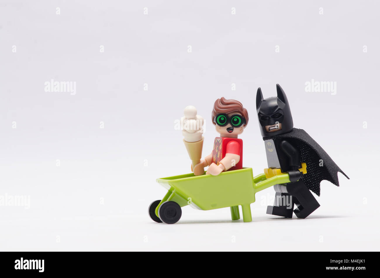 lego batman pushing wheelbarrow with robin sitting on it. isolated on ...