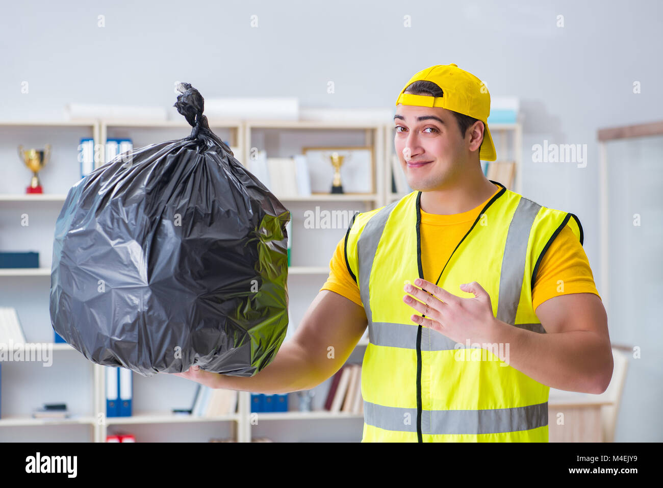 Man cleaning the office and holding garbage bag Stock Photo - Alamy