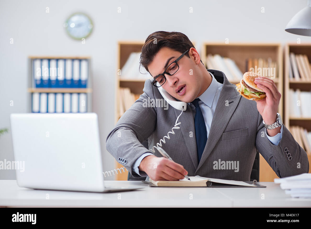 Hungry funny businessman eating junk food sandwich Stock Photo - Alamy
