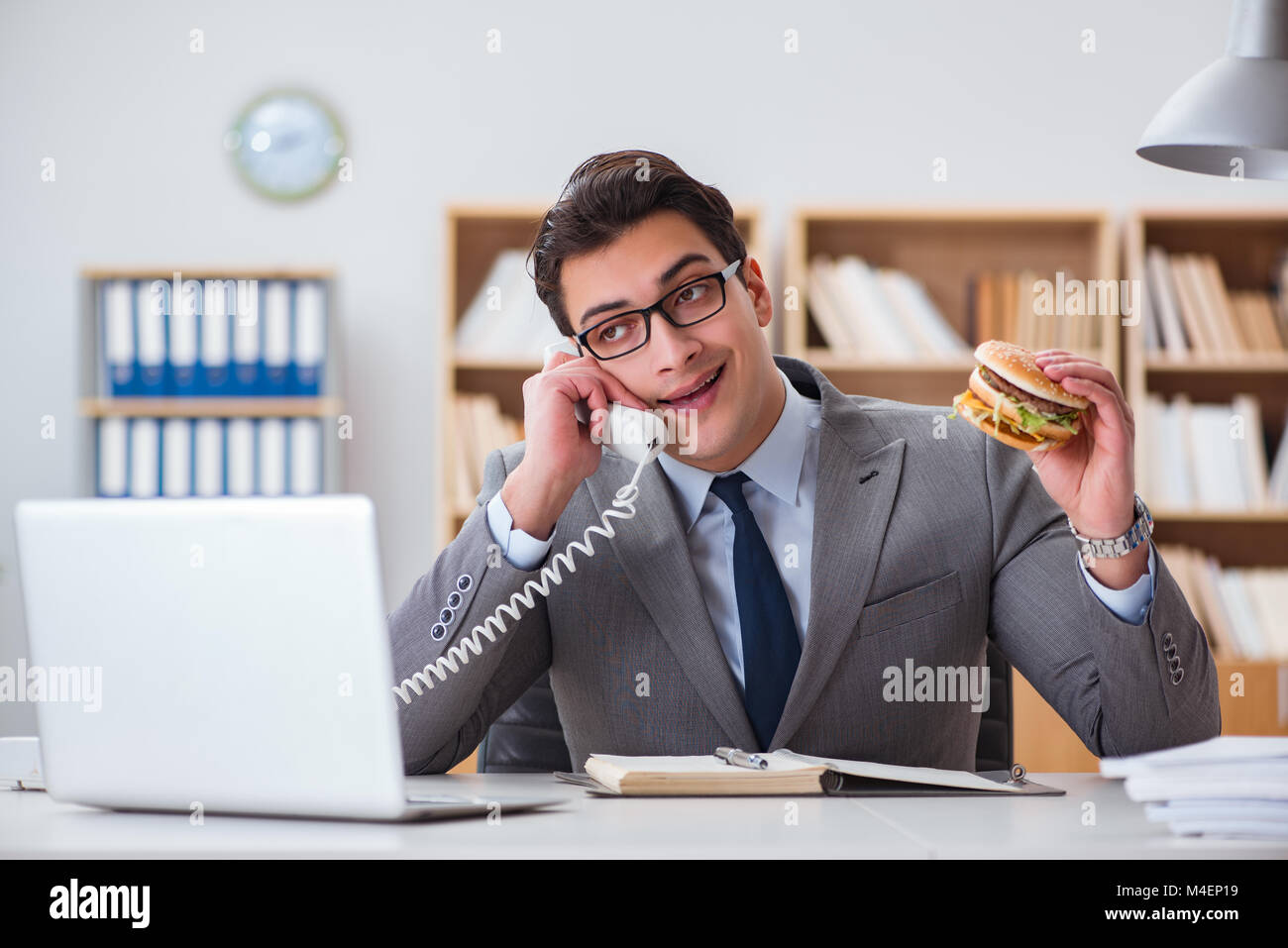 Hungry funny businessman eating junk food sandwich Stock Photo - Alamy