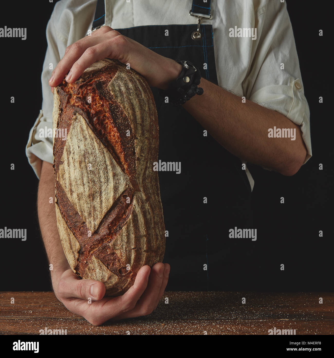 Baker's hands hold an oval bread Stock Photo - Alamy