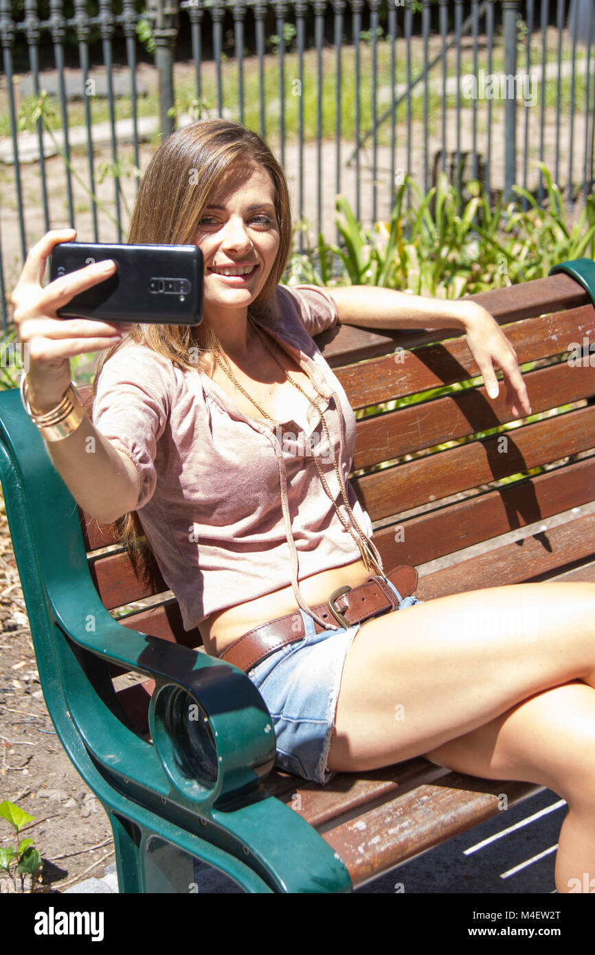 Caucasian female sitting on a bench video calling Stock Photo - Alamy