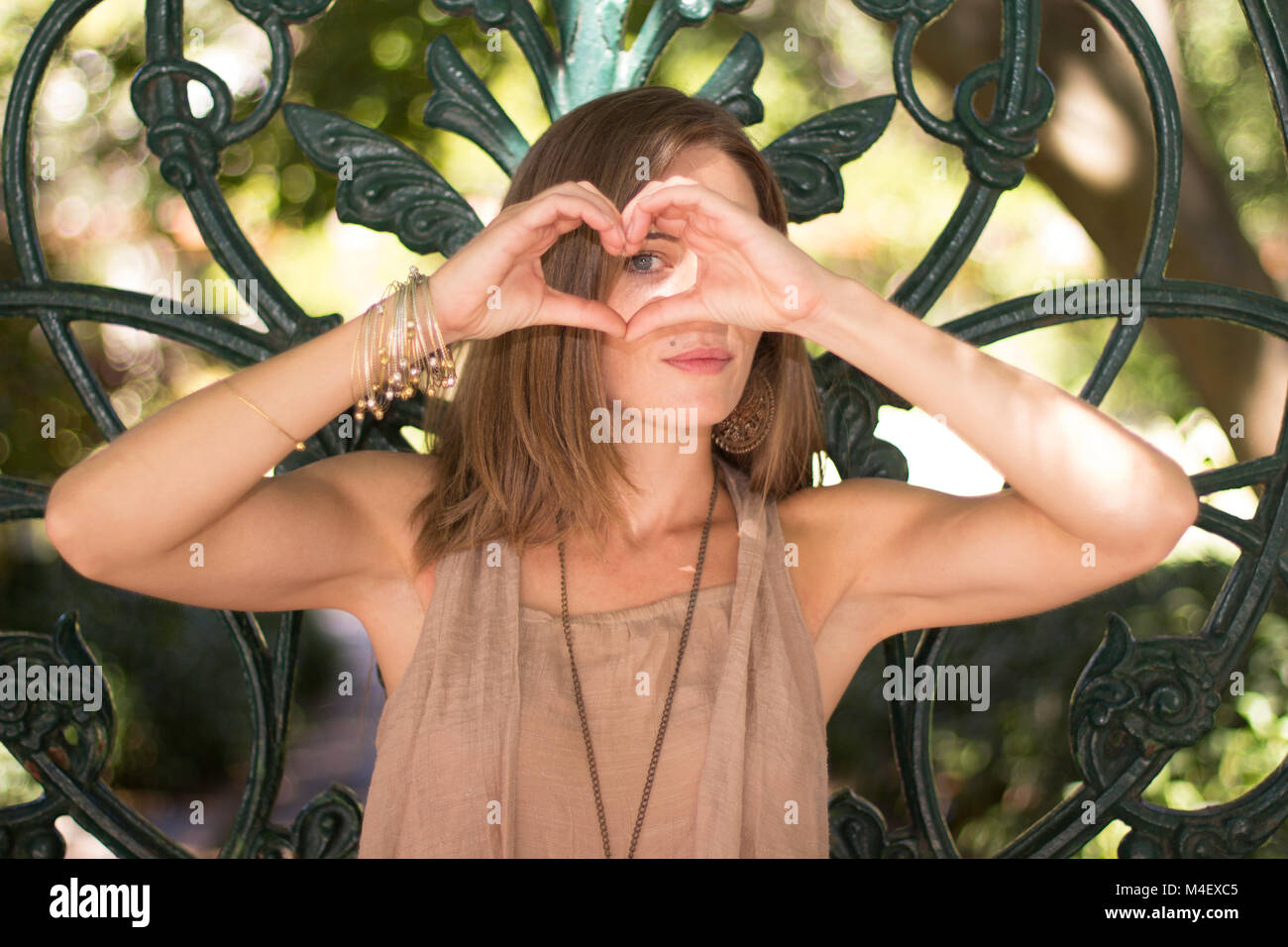Female looking through a heart shape made with her hands Stock Photo ...