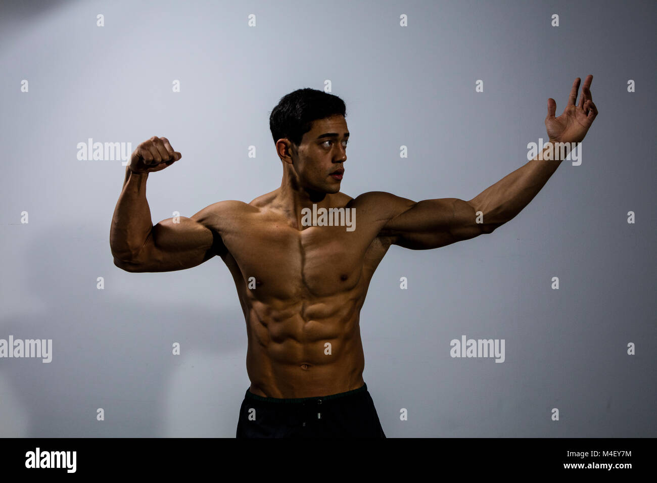 An Asian fitness model displaying his upper body physique. Medium shot ...