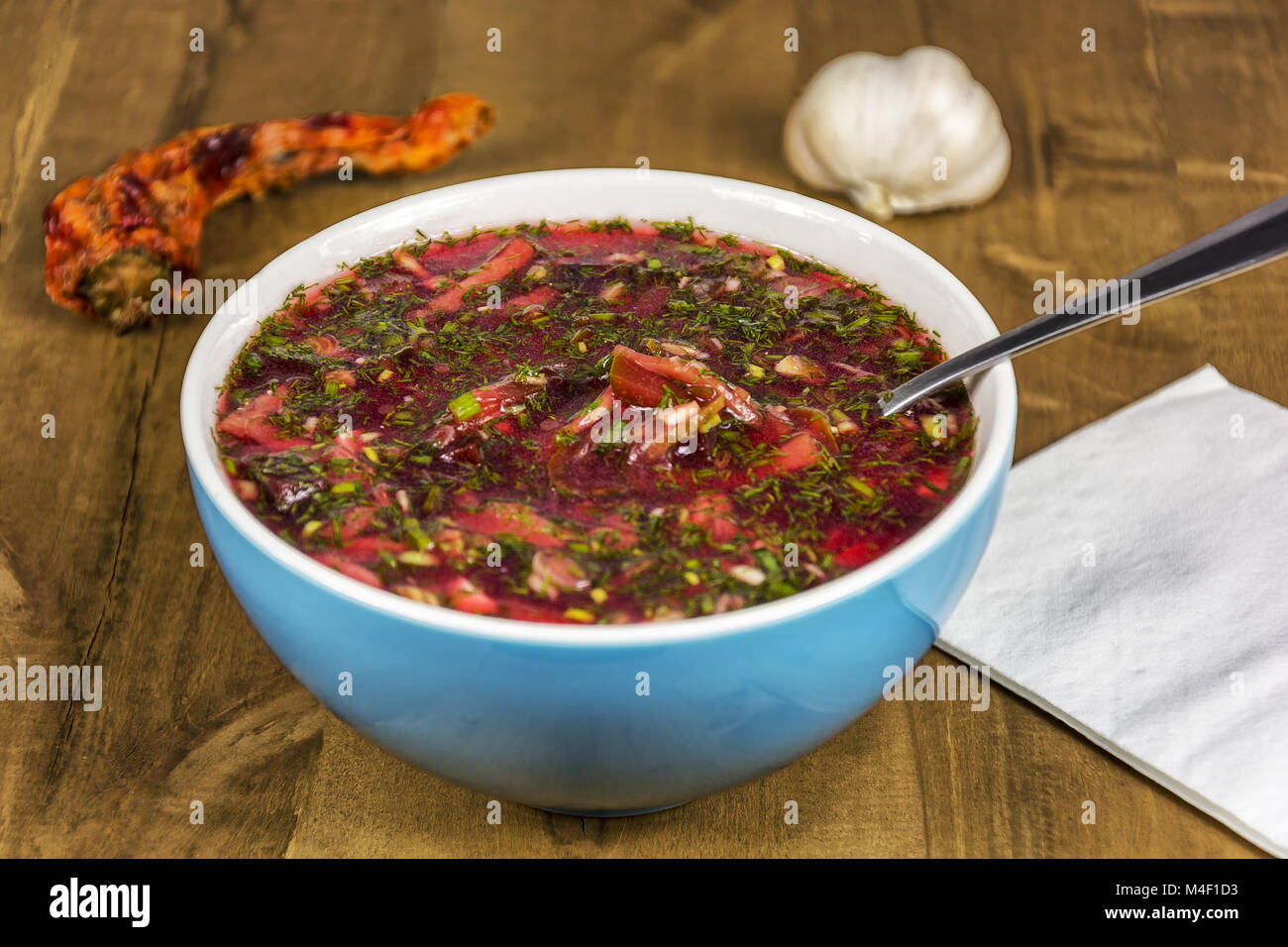 On a wooden table is a blue bowl of borscht Stock Photo - Alamy