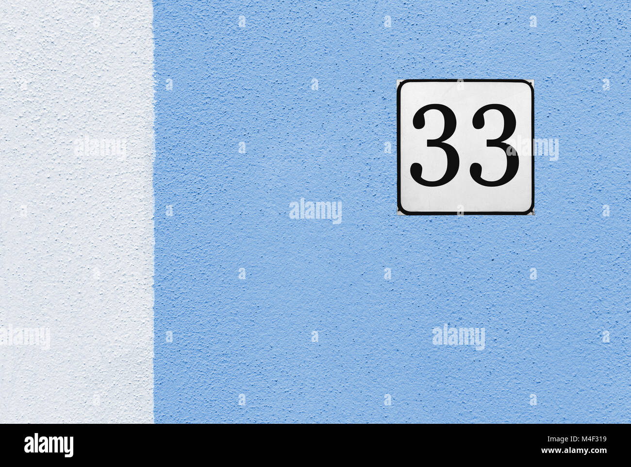 Street number 33 sign on a white and yellow house exterior wall Stock ...