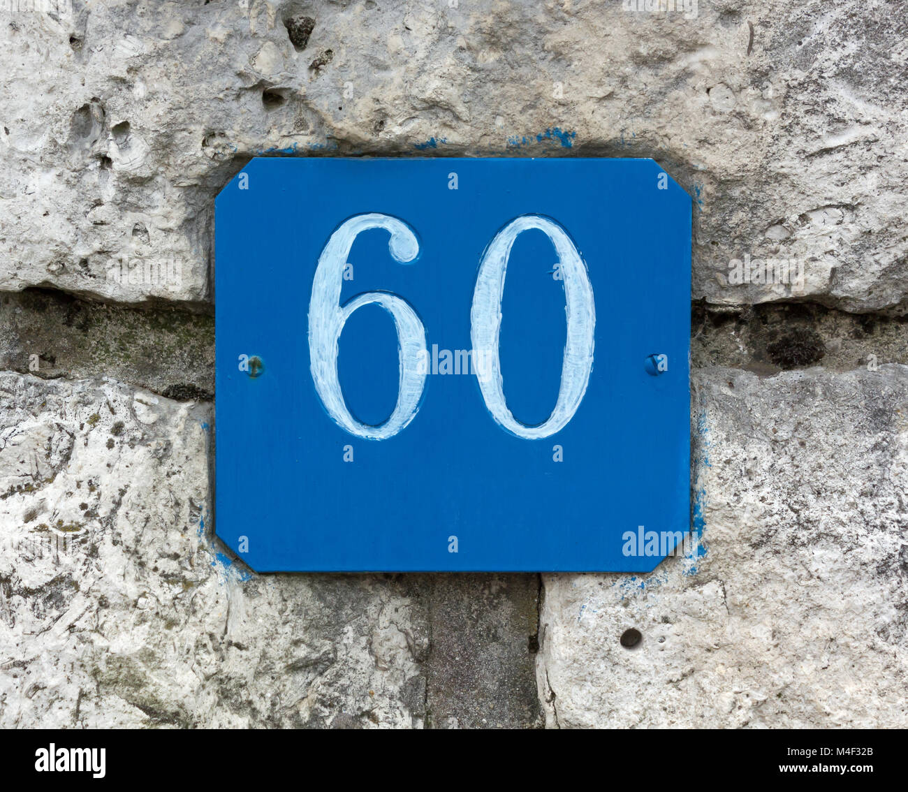 Blue colored street number 60 sign on a stone wall Stock Photo - Alamy
