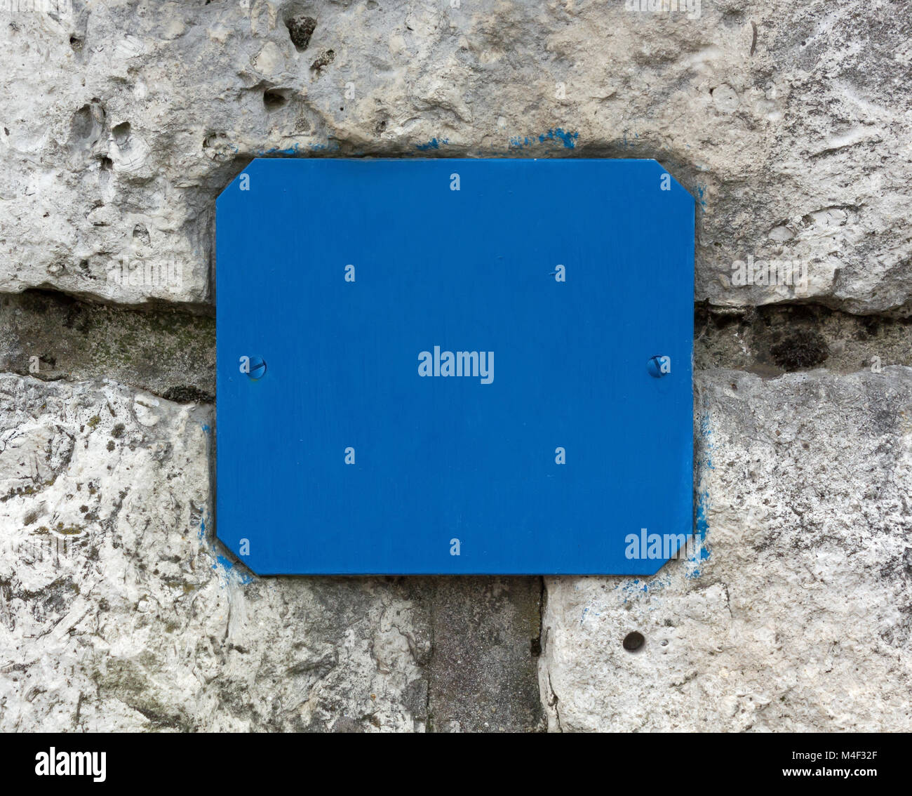 Blue colored blank street number sign on a stone wall Stock Photo - Alamy