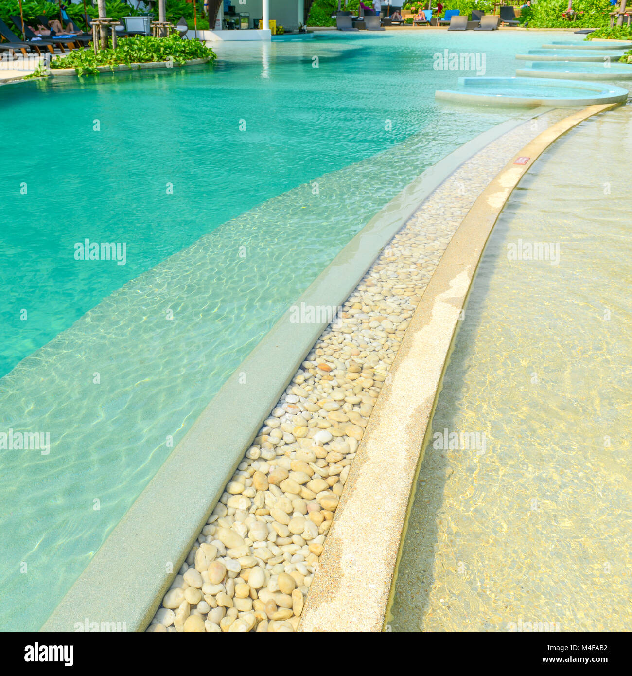 Closeup of stone border in front of bright blue swimming pool ...