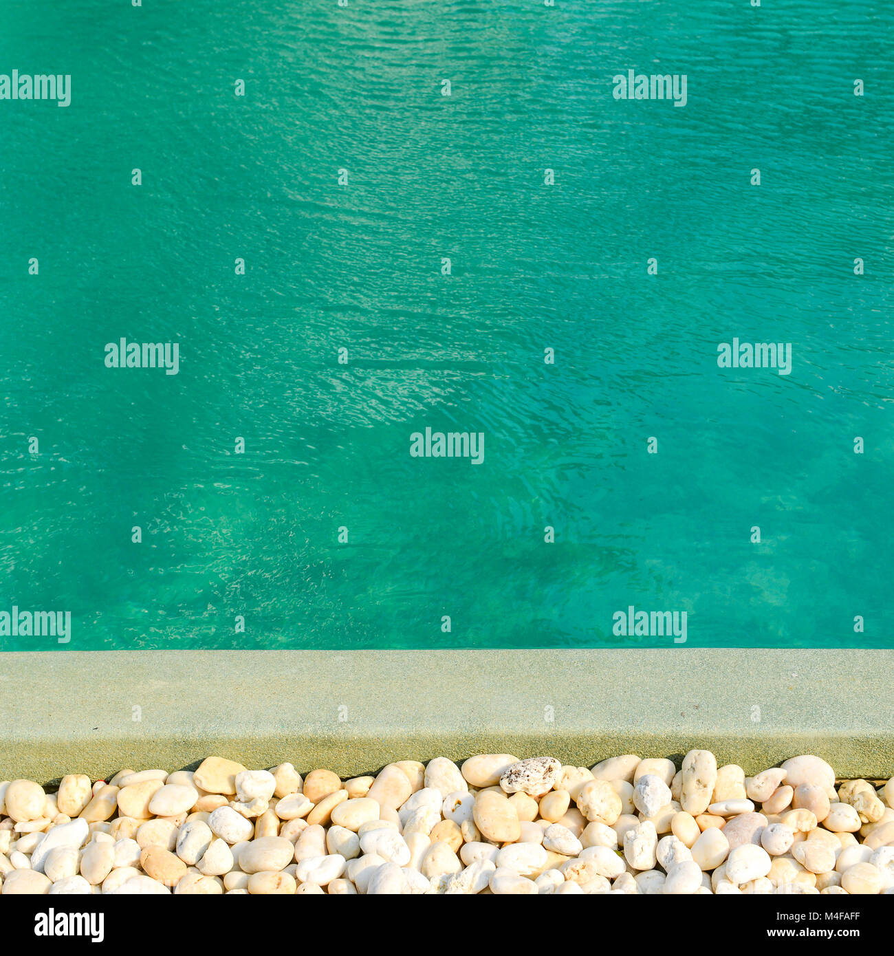 Closeup of stone border in front of bright blue swimming pool ...