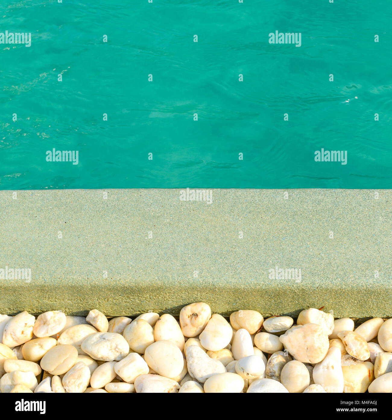 Closeup of stone border in front of bright blue swimming pool ...